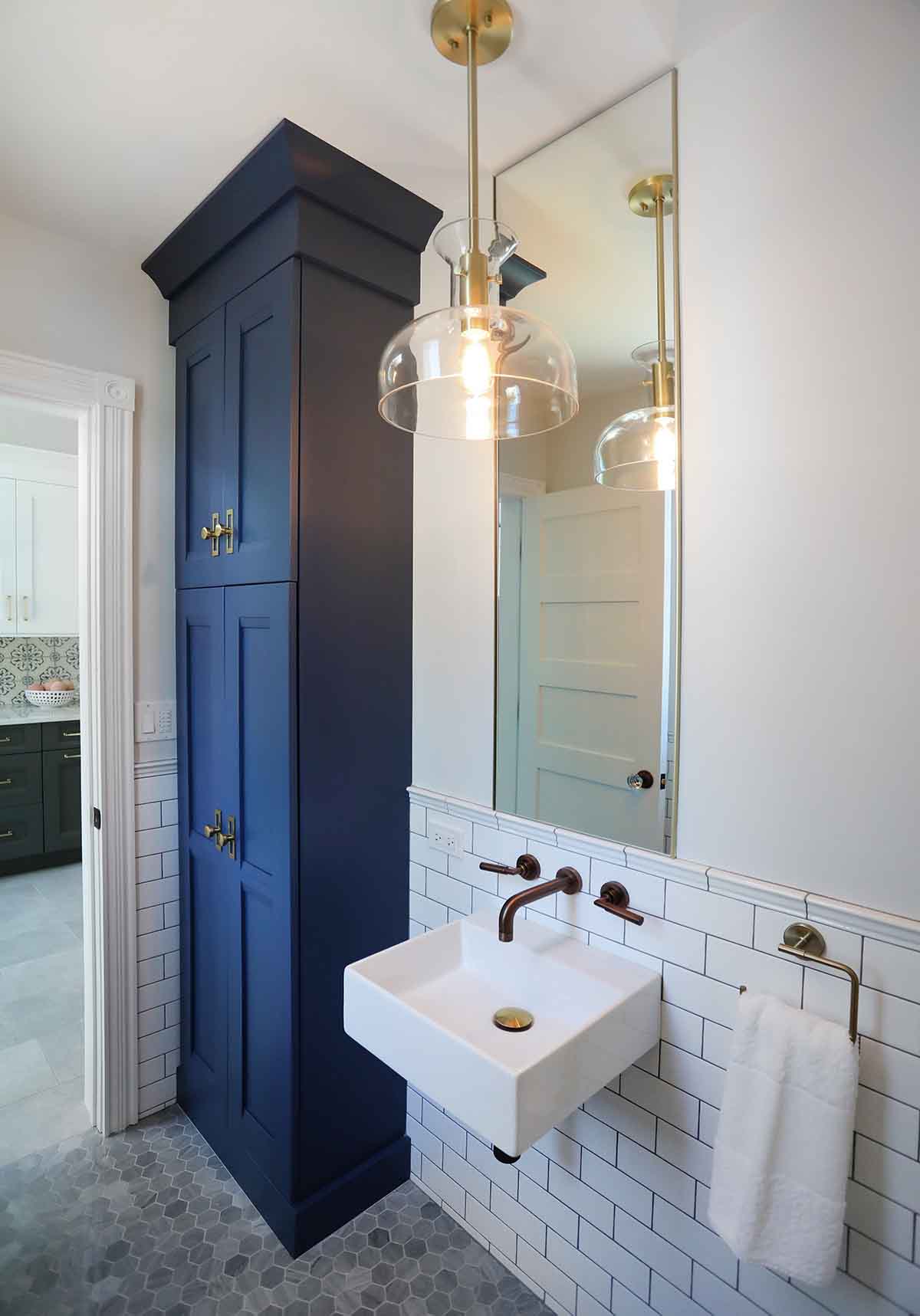 Powder room, tall ble cabinetry, gold light pendant and brass fixtures